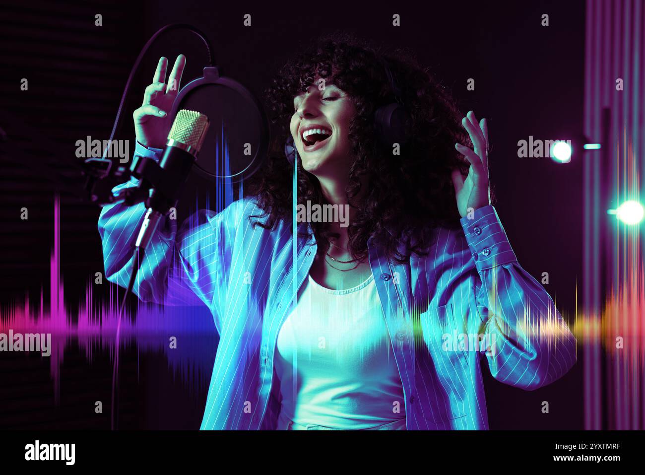 Vocalist with headphones singing into microphone in professional record ...