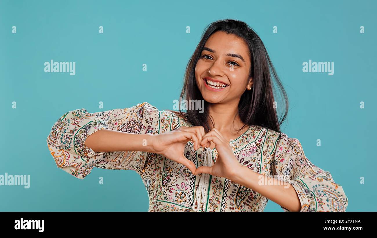 Portrait of smiling loving woman doing heart symbol shape gesture with ...