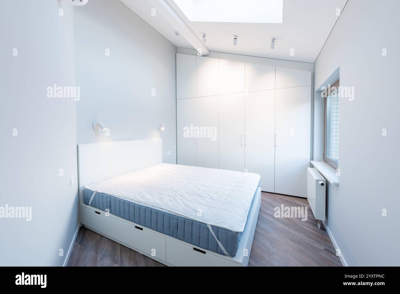 Bright and clean bedroom featuring a cozy bed, white built-in wardrobe ...
