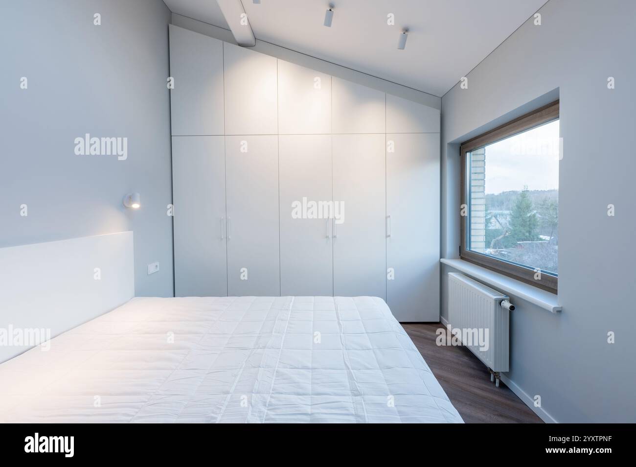 Bright and clean bedroom featuring a cozy bed, white built-in wardrobe ...