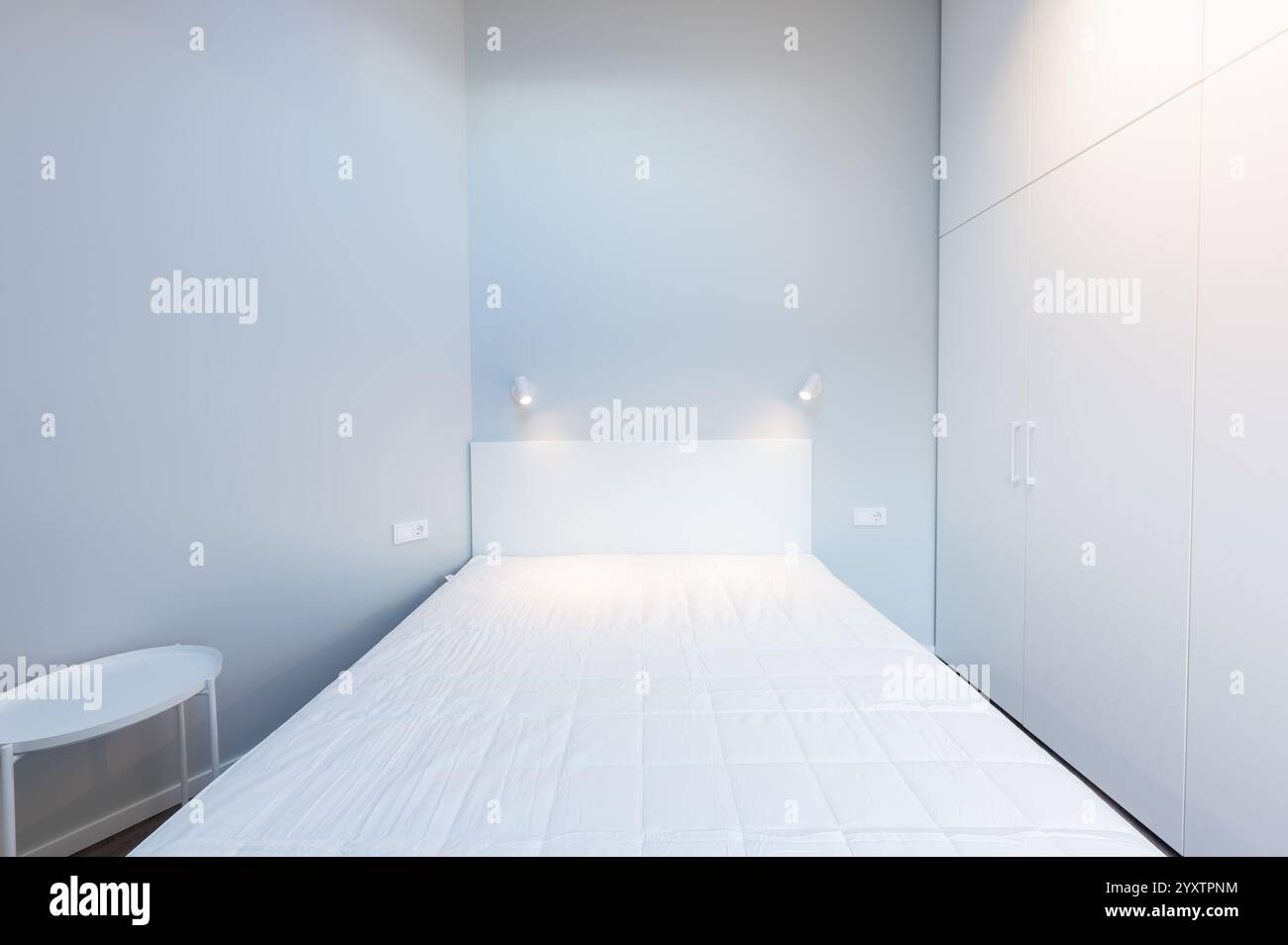 Bright and clean bedroom featuring a cozy bed, white built-in wardrobe ...