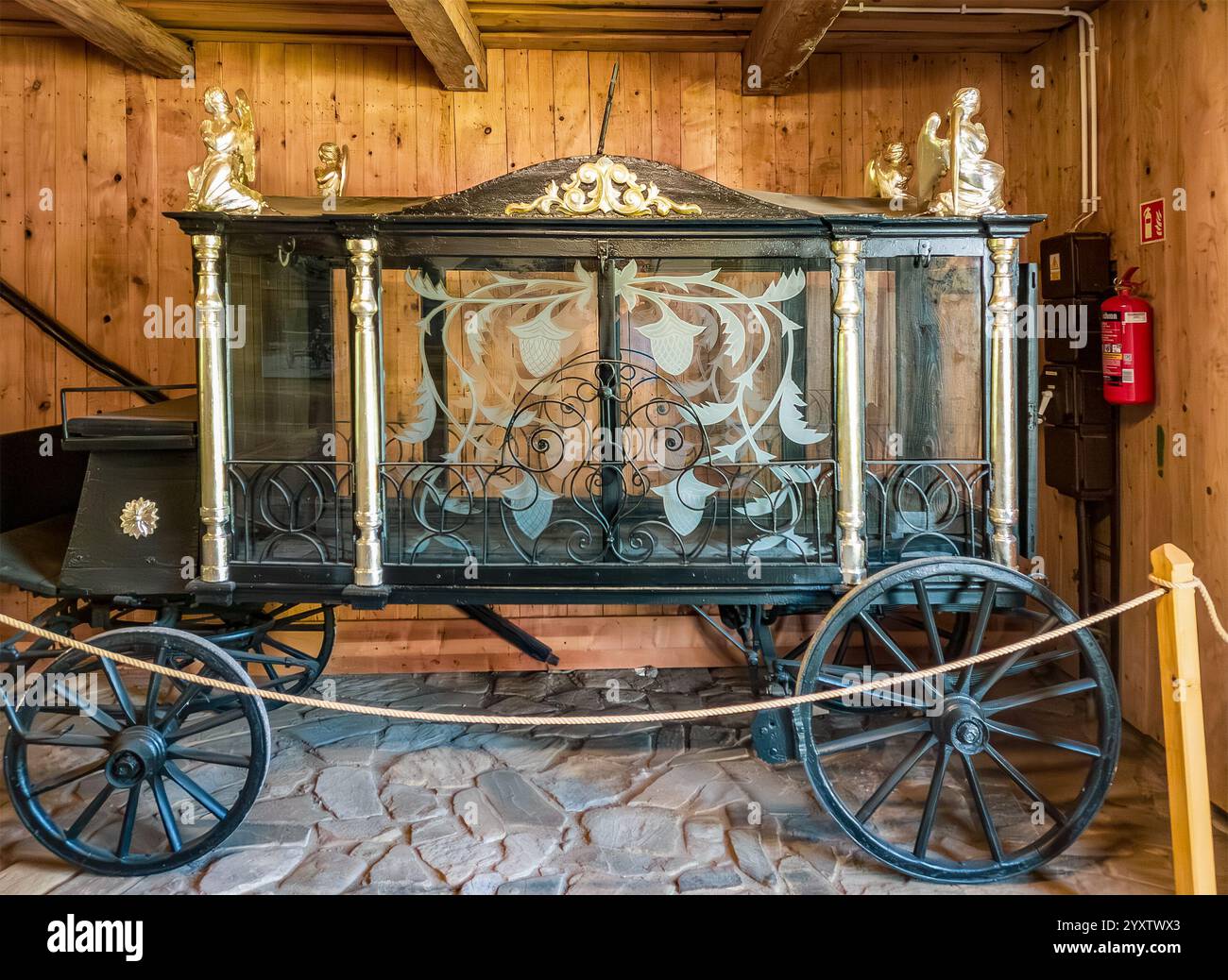 An antique, ornate hearse carriage is displayed in a wooden barn in the ...
