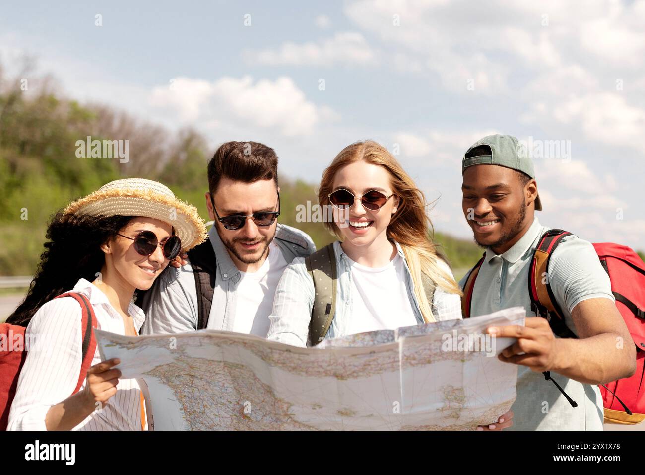 Group of multinational young friends looking at map, choosing route ...