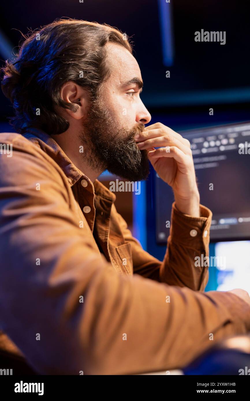 Cybersecurity professional anxiously looking at computer screen, trying ...