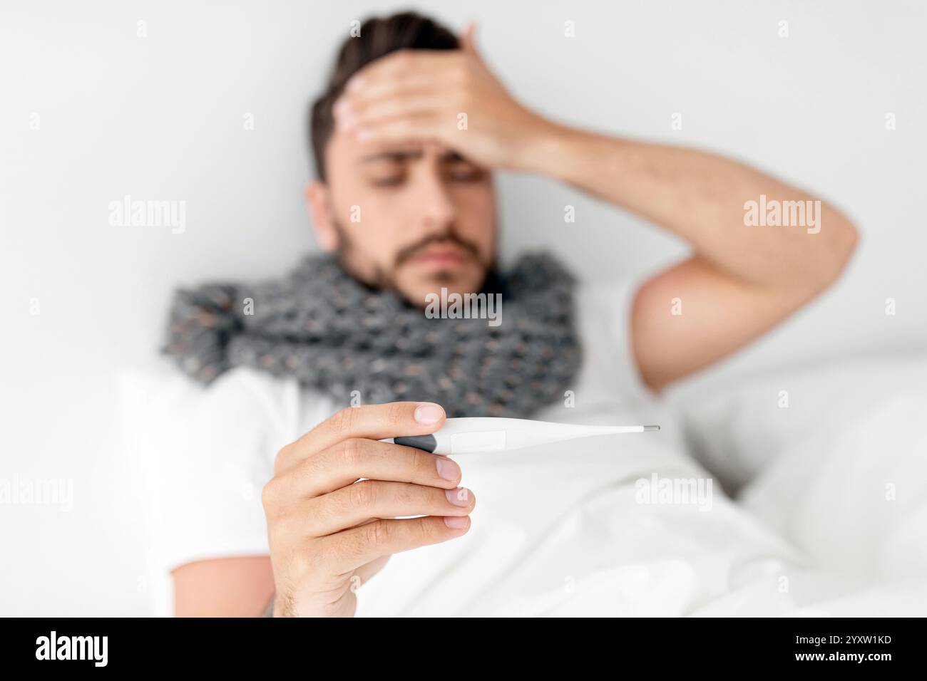 Sick man checking body temperature holding thermometer and touching ...