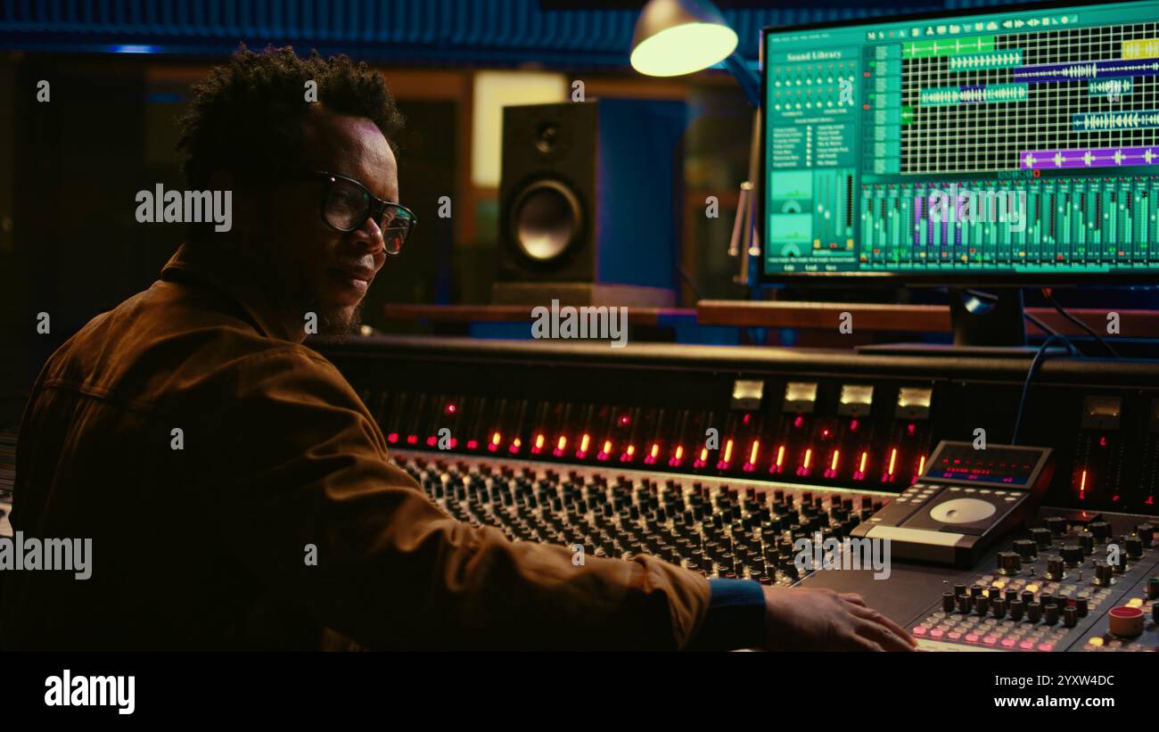 Portrait of african american audio technician uses mixing console with ...