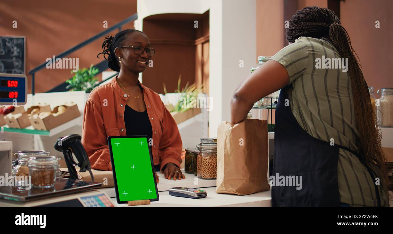 Woman approaching checkout with greenscreen on tablet, buying natural ...