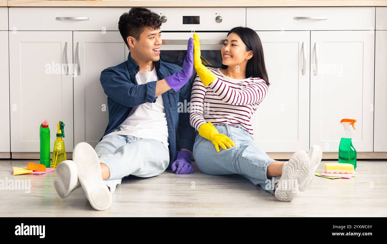 Tired asian couple sitting in kitchen, giving high five Stock Photo - Alamy