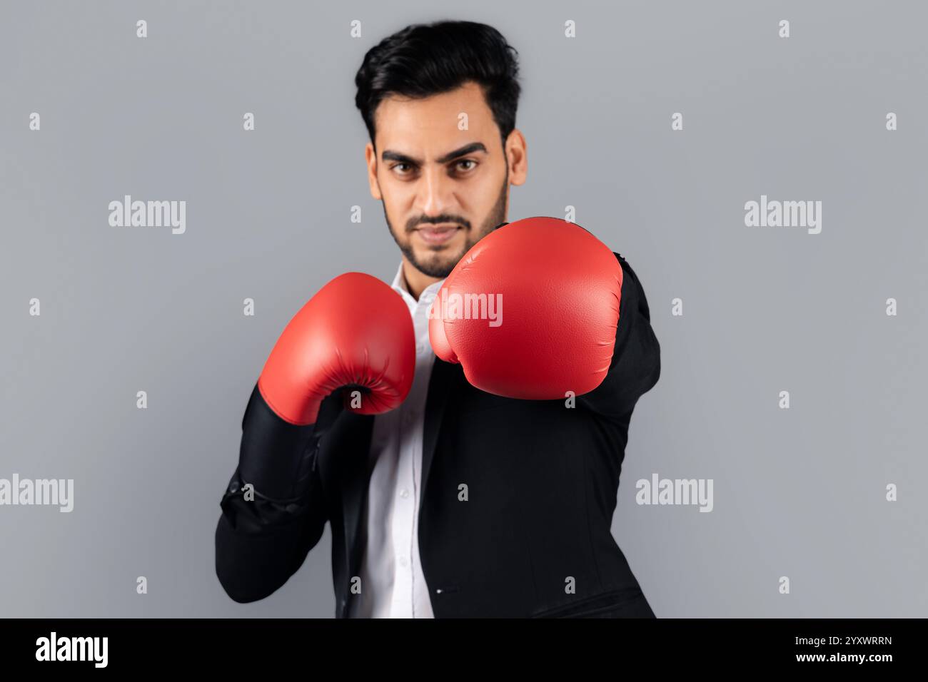 Middle Eastern businessman in a suit striking a boxing pose in studio ...