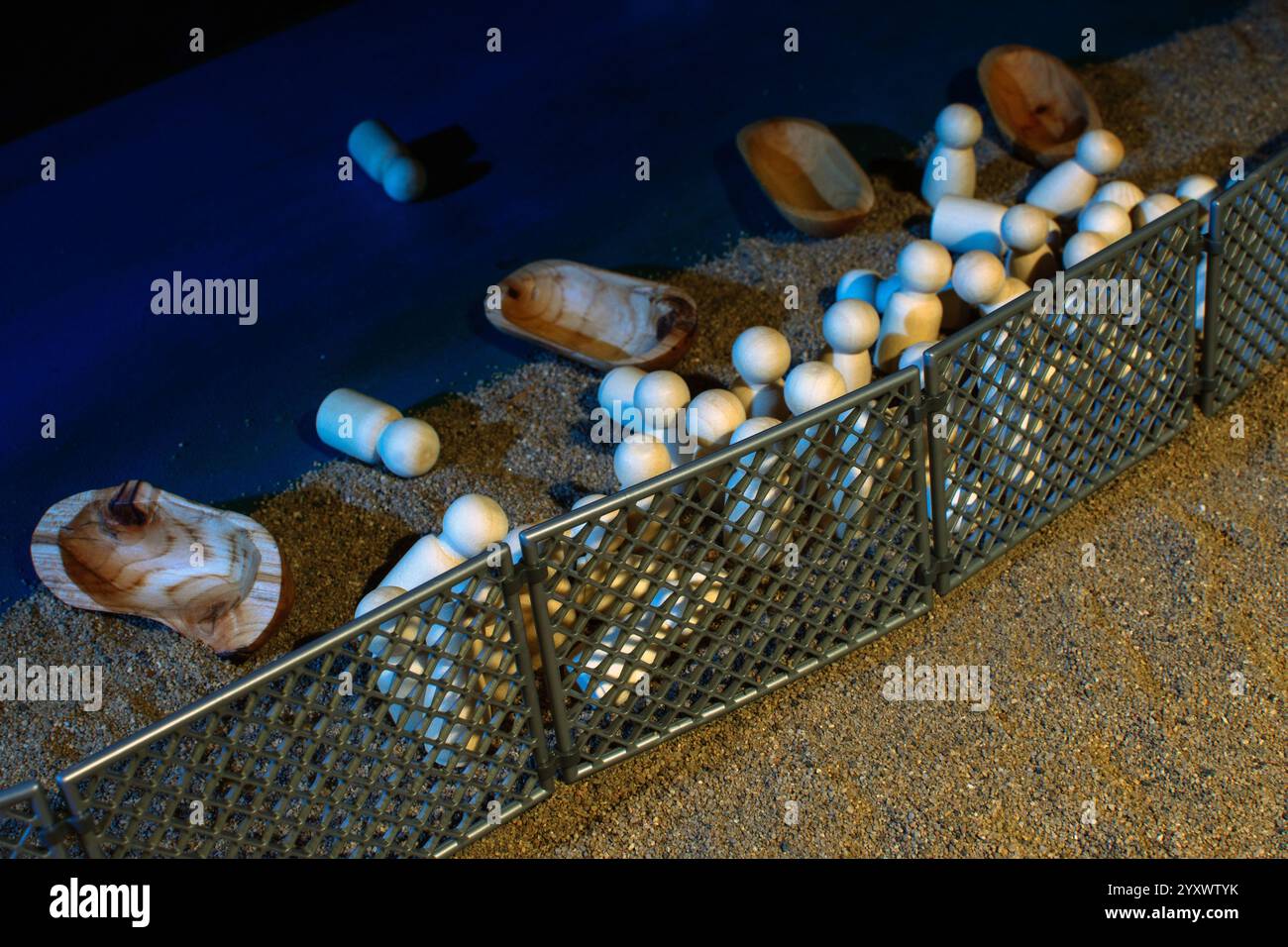 Wooden Figures Clustered Behind a Fence on Sand Stock Photo - Alamy