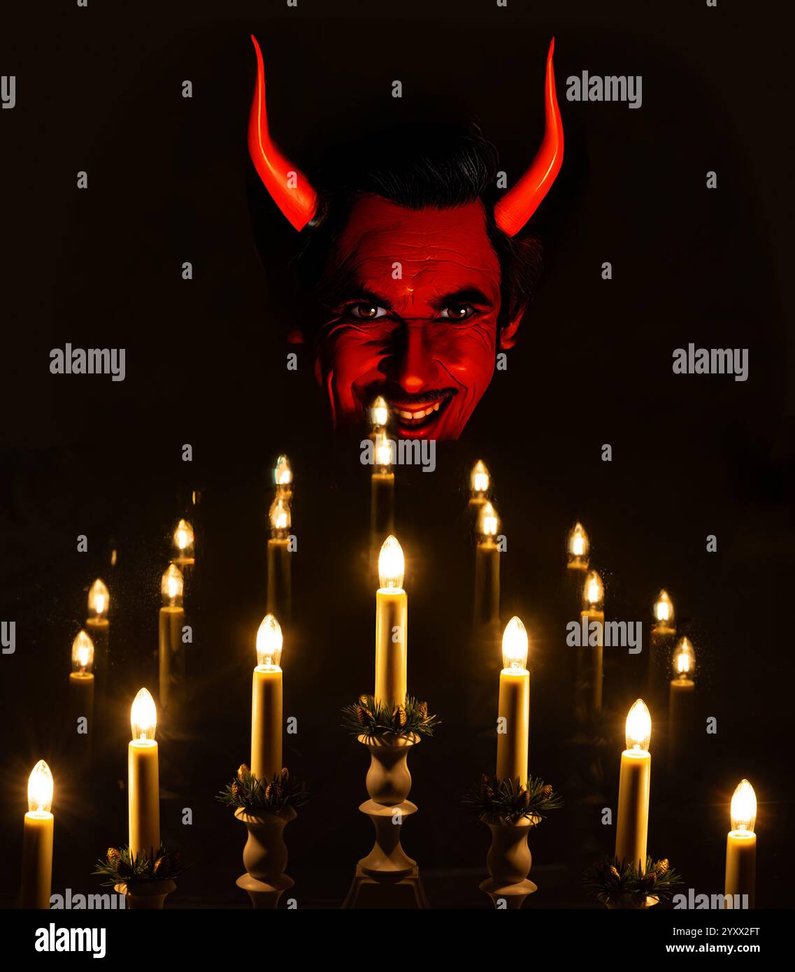 The red face of the devil in the darkness behind the candlestick, which ...