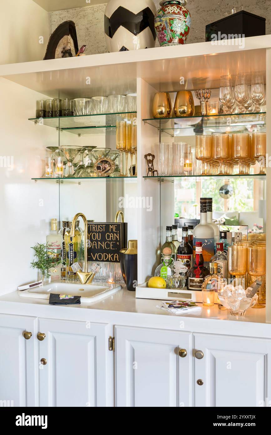 Home bar set up in built-in cabinet with mirror back and glass shelves ...