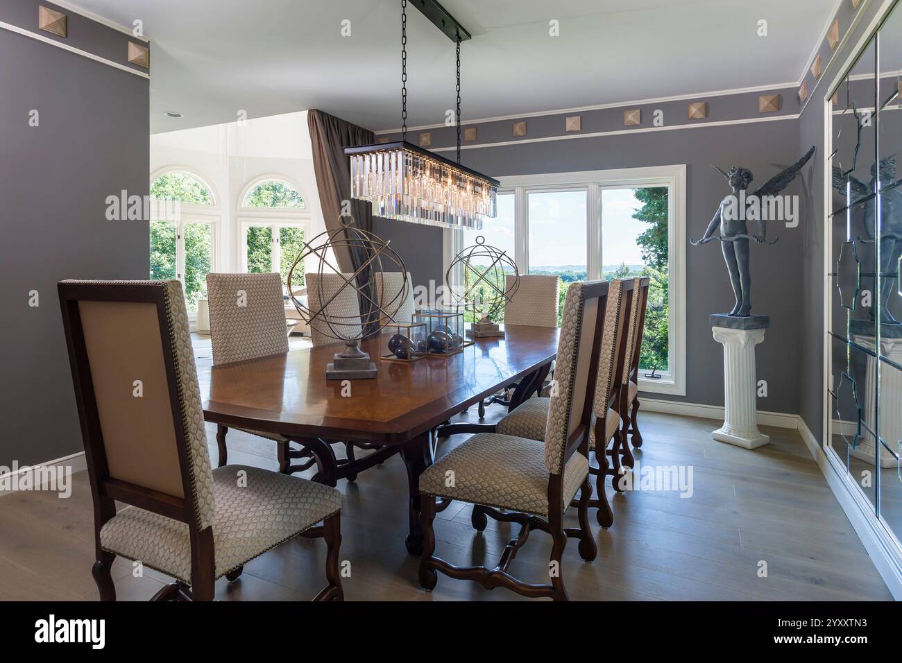 Formal dining room with large table and eight high back chairs and angel statue in the corner ...