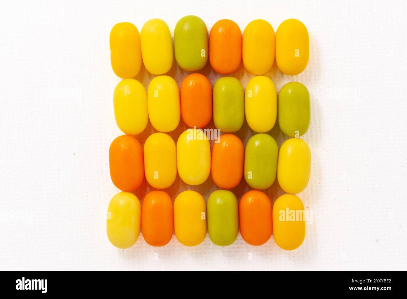 A row of yellow and green candies. The candies are in a row and are all ...