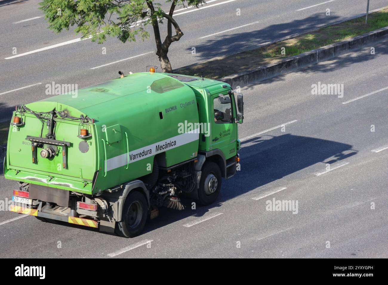 Green street sweeper truck cleaning a multi lane highway on a sunny day ...