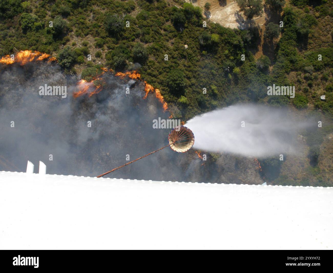 A firefighting helicopter dumps buckets of water to extinguish a forest ...