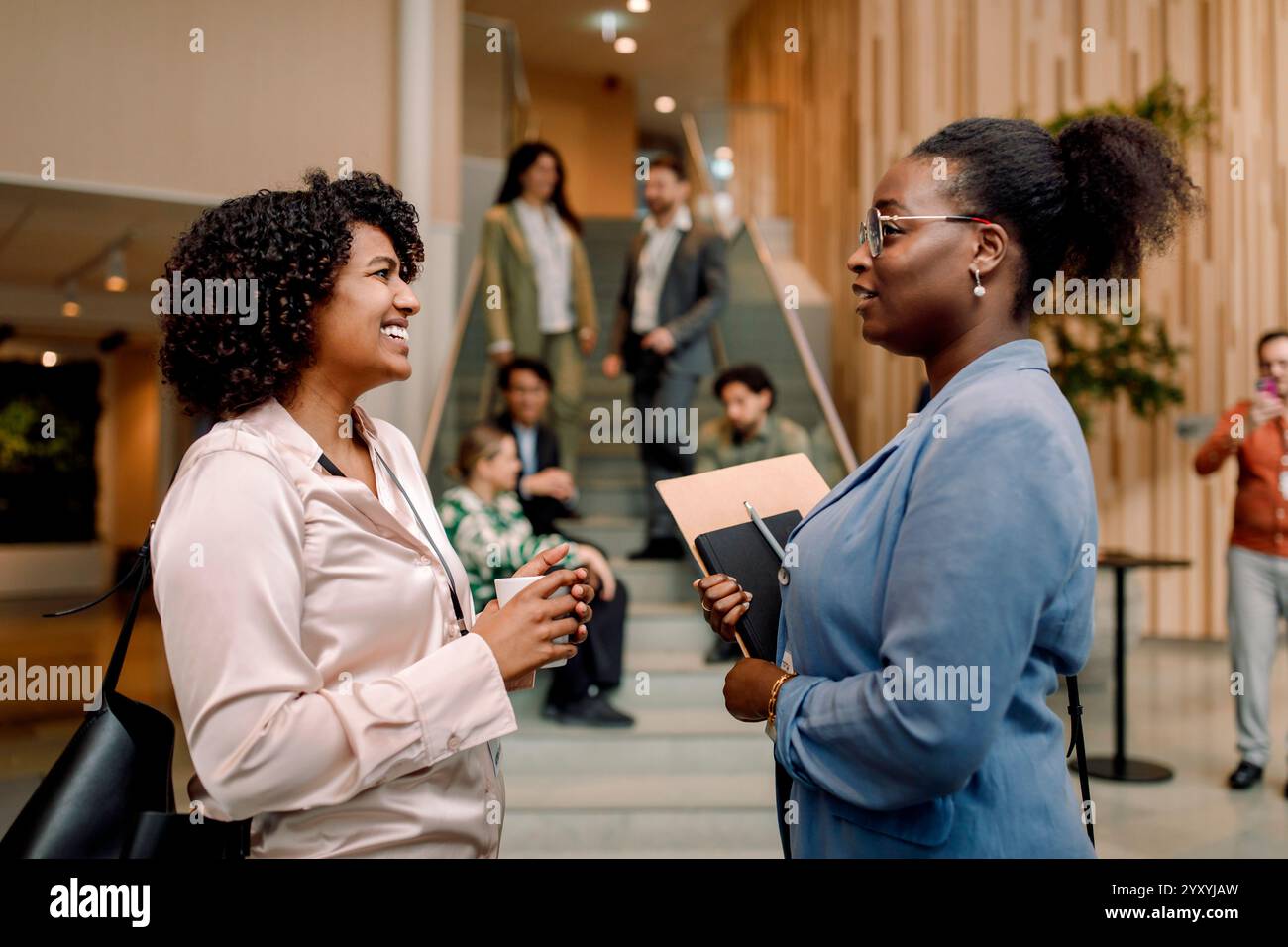 Smiling female business entrepreneurs talking to each other at ...