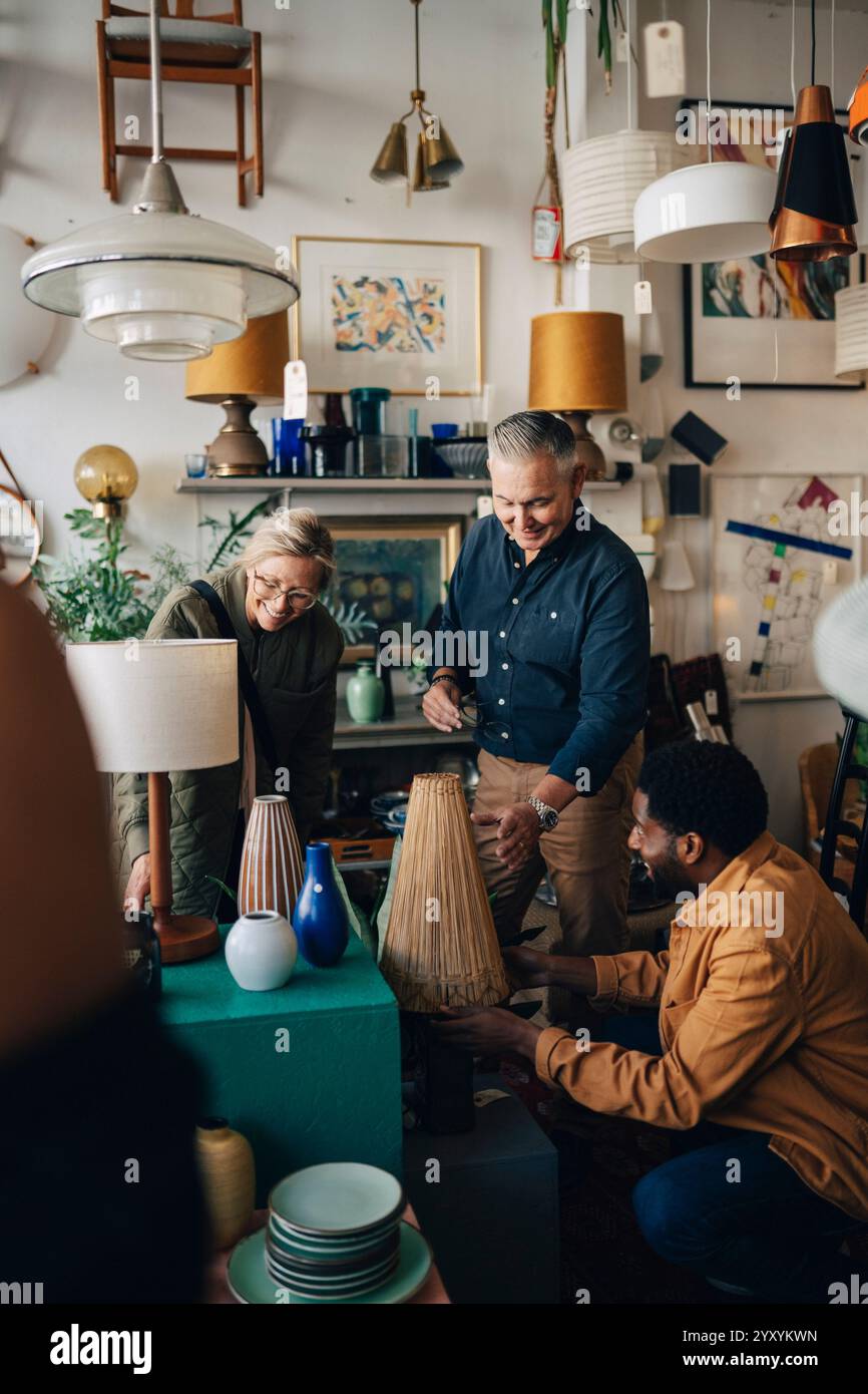 Senior male owner assisting customer doing shopping at antique store ...