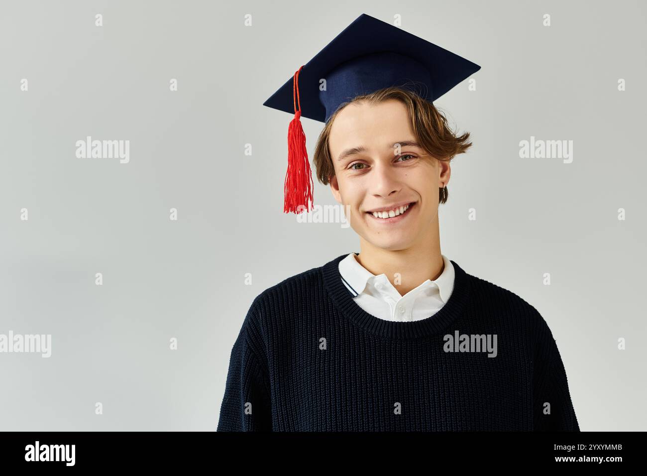 A young man smiles proudly in graduation cap, reflecting on his college ...