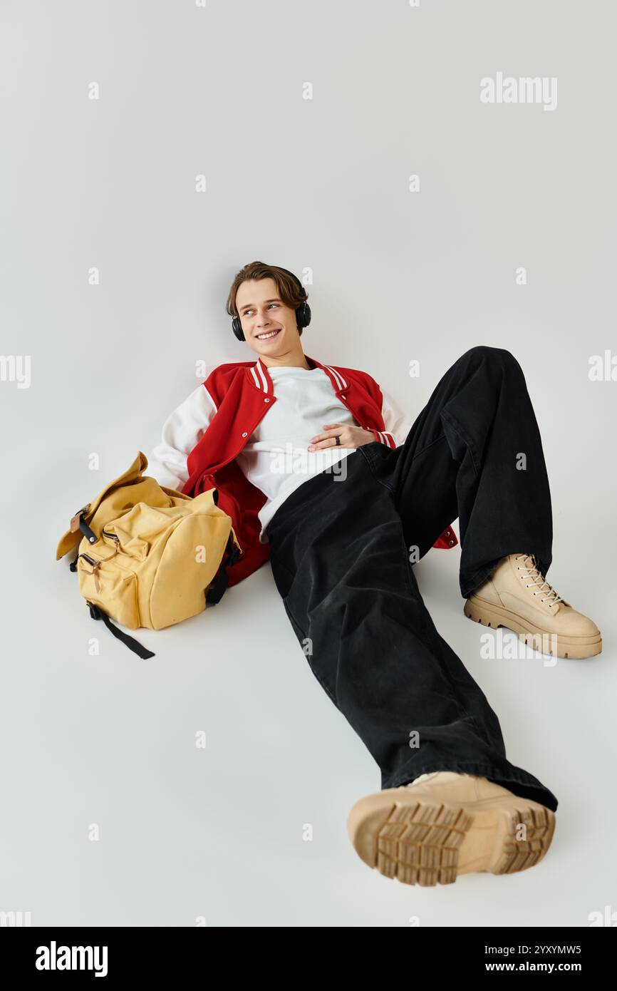 Young man lounges comfortably on the floor, showcasing his fashionable ...