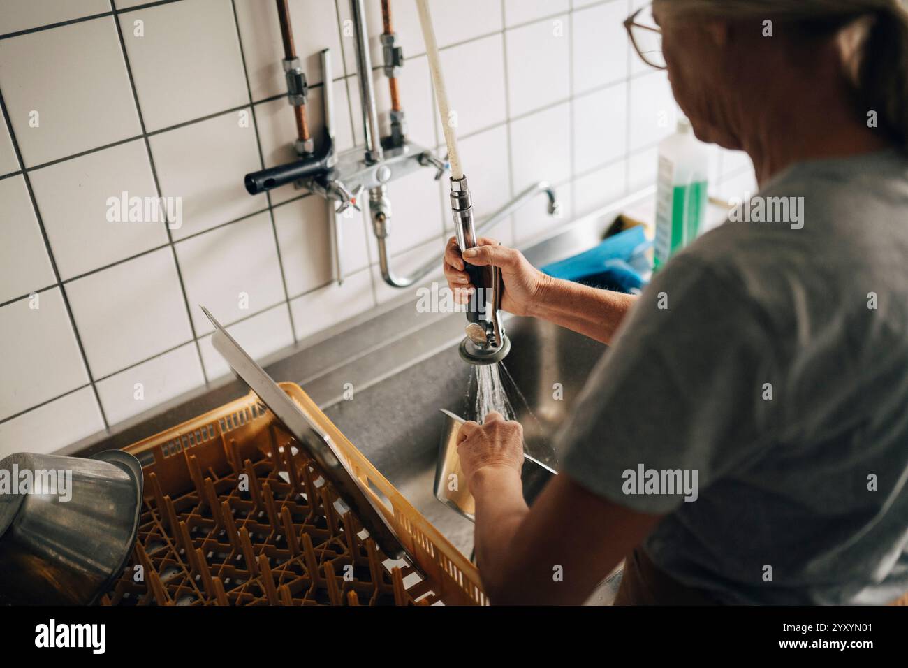 High angle view of senior female baker spraying water on dishes while ...