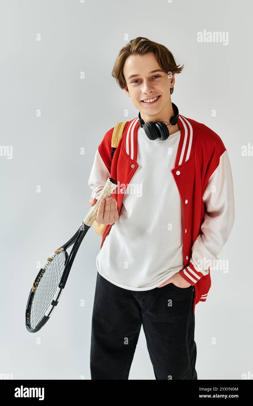 A stylish young man shows off his bomber jacket and holds a tennis ...