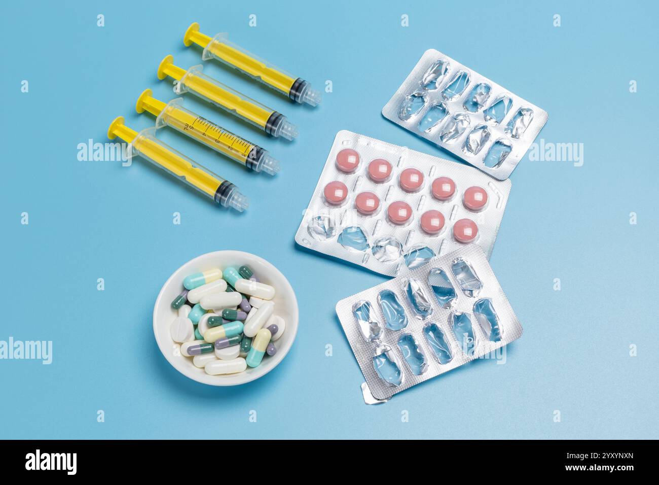 Empty and used medicine blister packs with pink pills and syringes ...