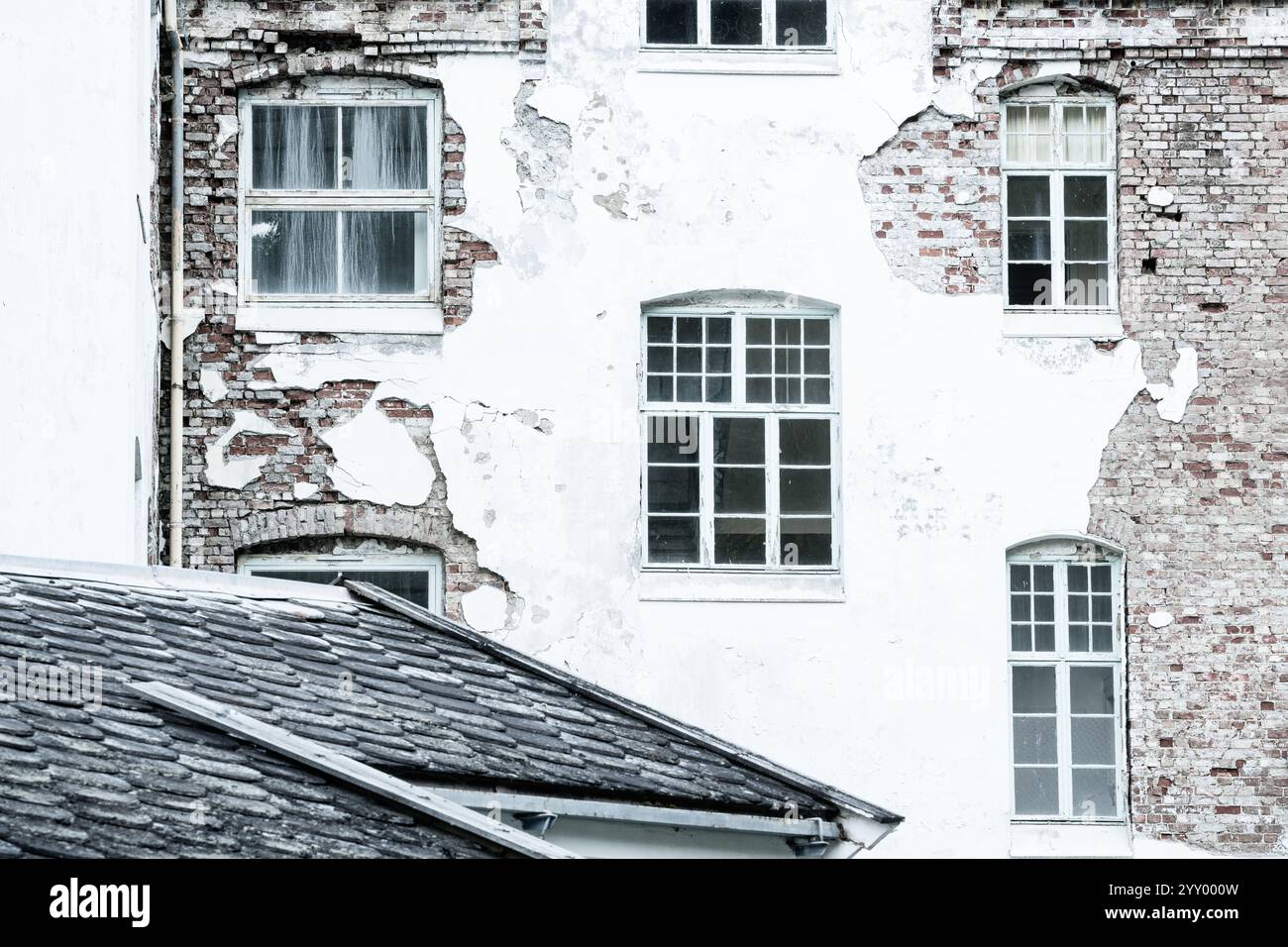 The weathered exterior of a dilapidated sanatorium in Norway reveals cracks and peeling paint ...