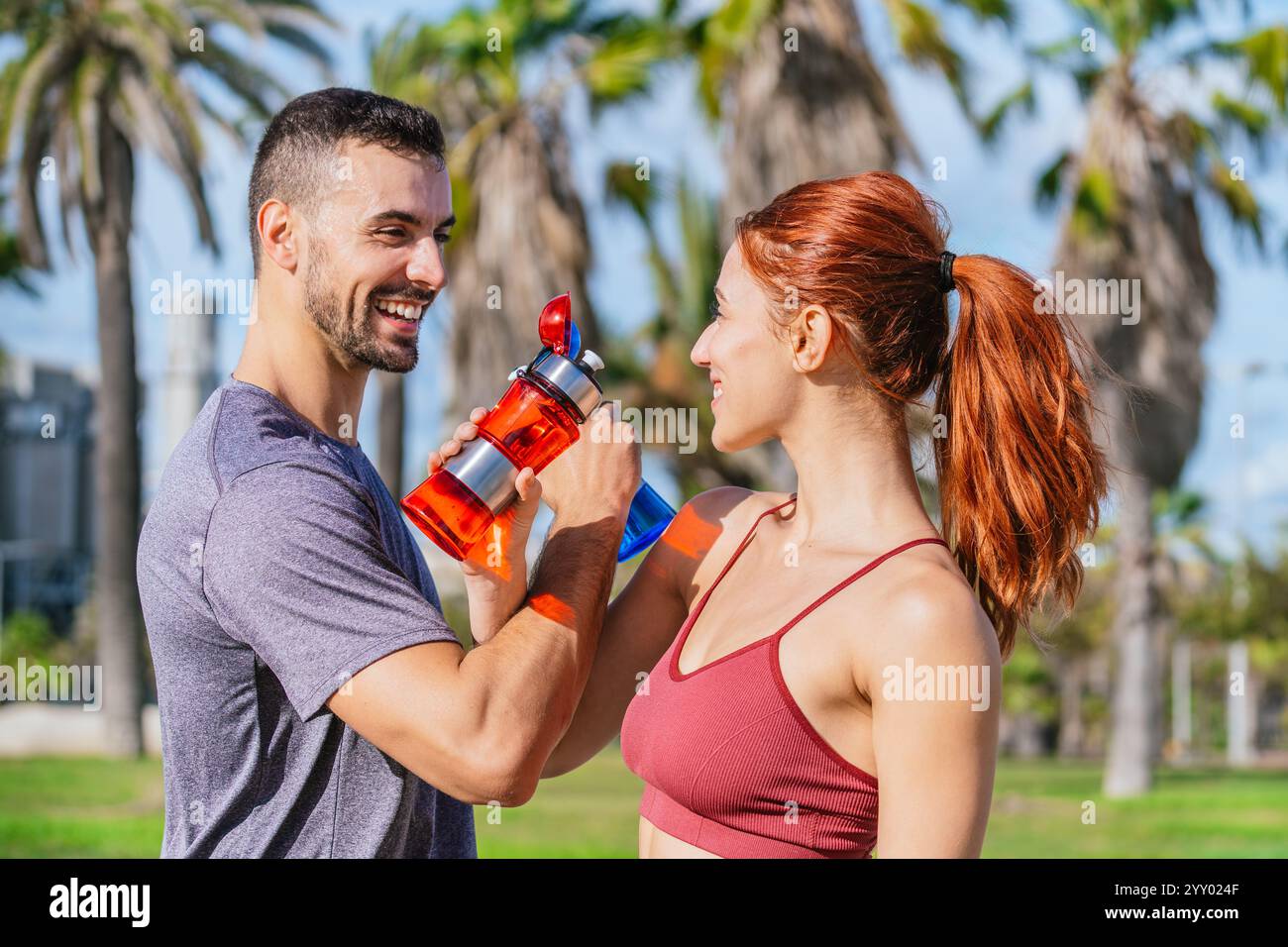 Fit Couple Smiling and Sharing a Water Break Outdoors Stock Photo - Alamy