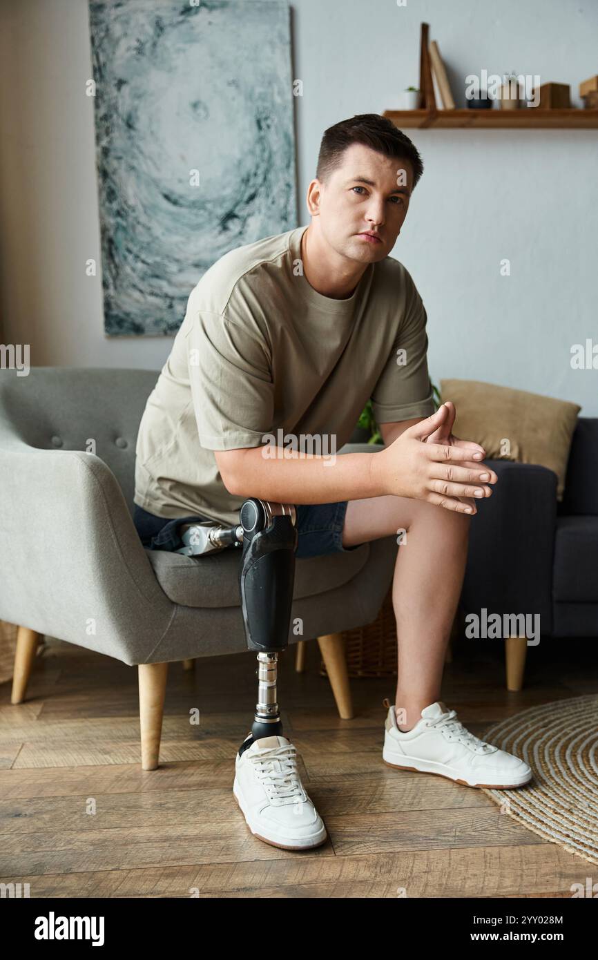 Handsome young man sits on a couch, showcasing his prosthetic leg with ...