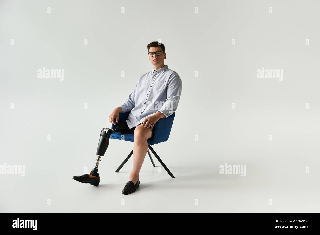 Handsome young man with a prosthetic leg poses comfortably in a modern ...