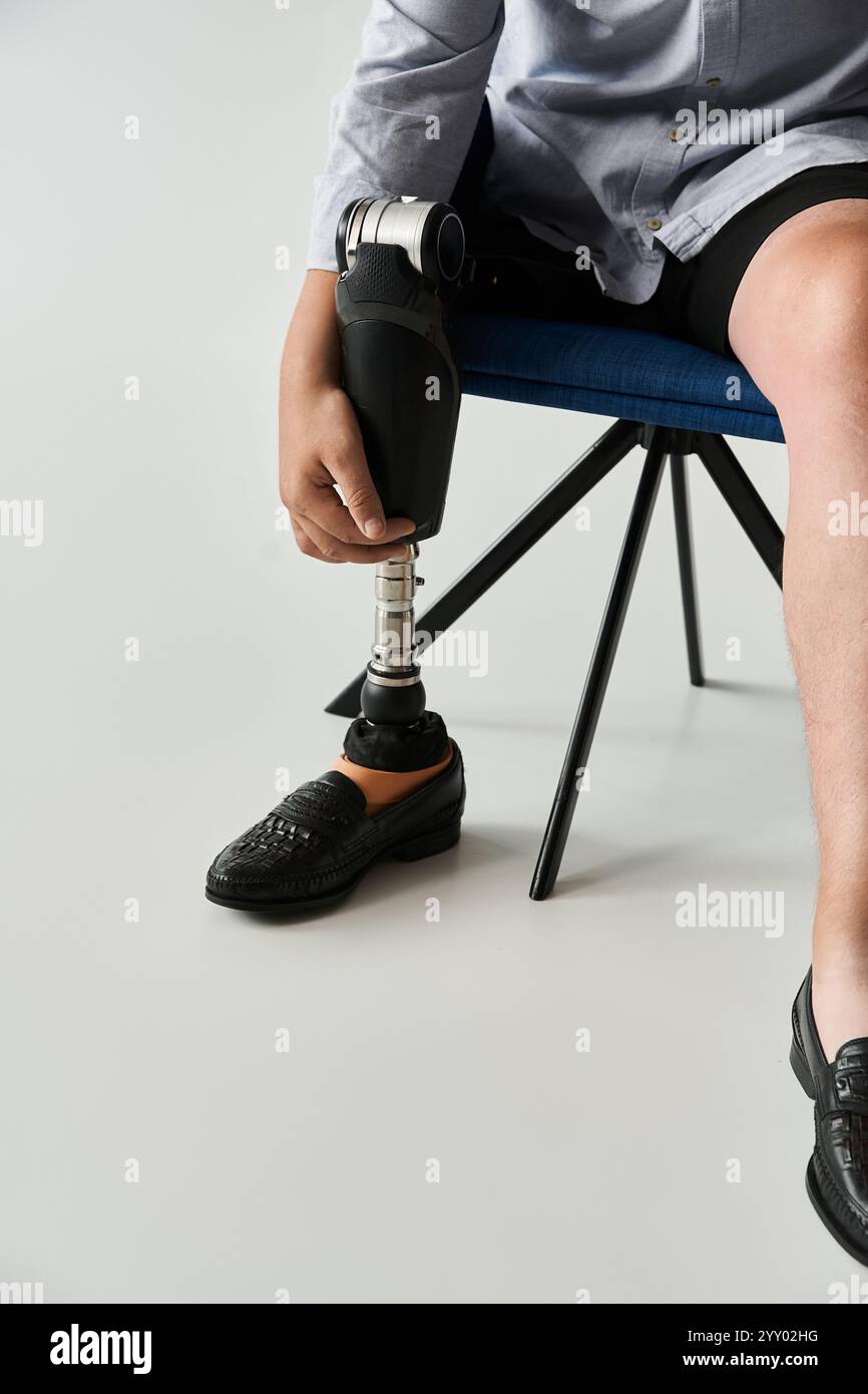 Young man adjusts his stylish prosthetic leg while sitting casually on ...