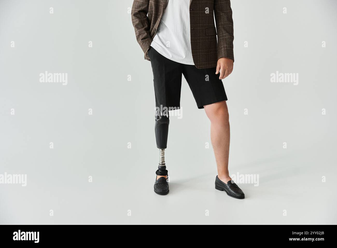 A young man with a prosthetic leg stands confidently, dressed in modern ...