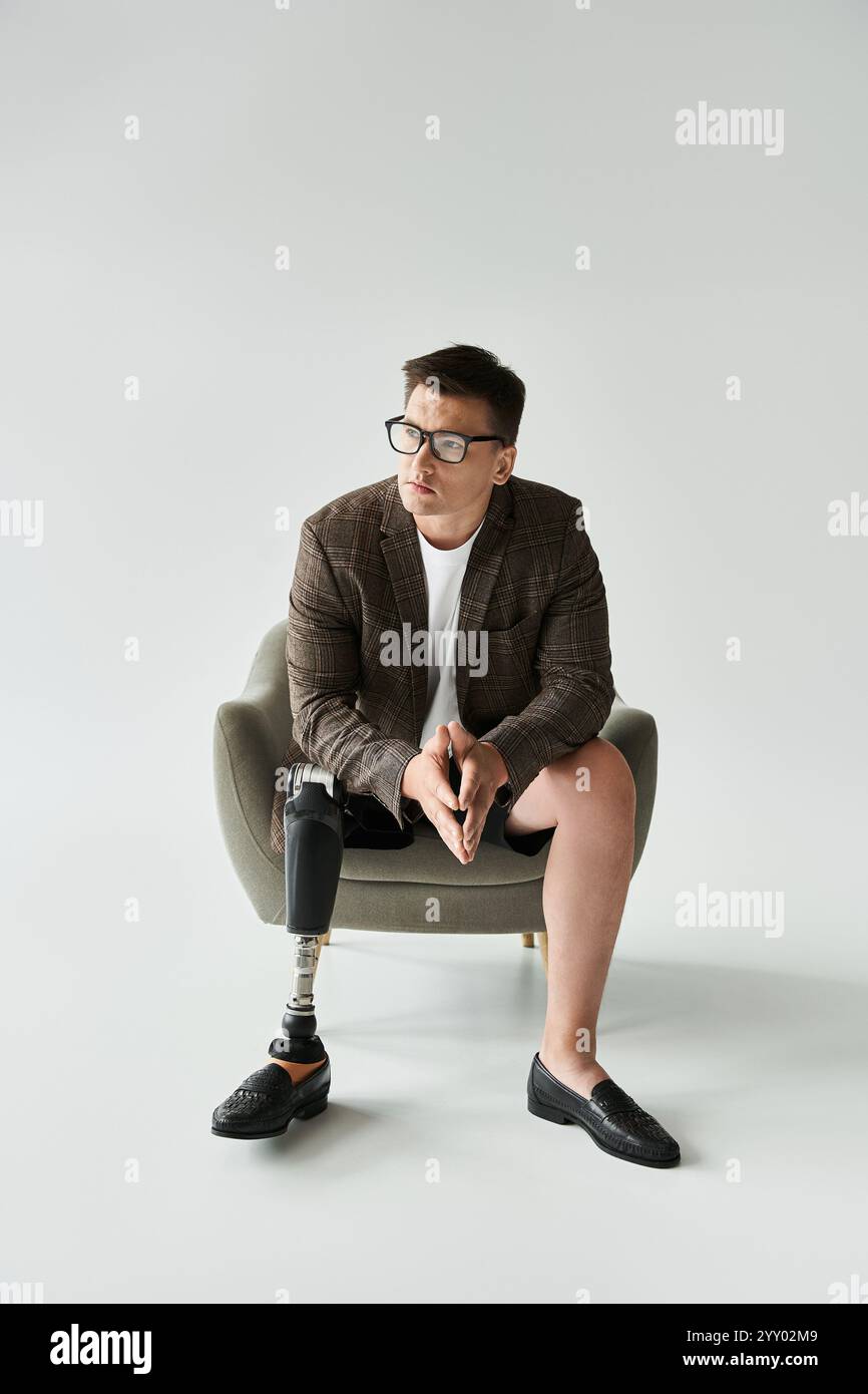 Man with a prosthetic leg is sitting thoughtfully in a modern chair ...