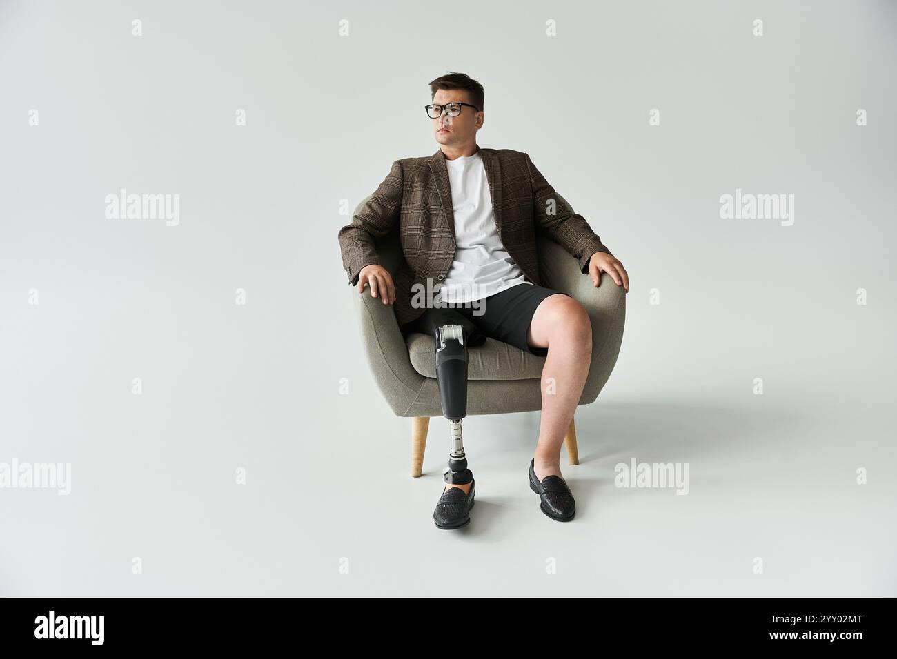 Man sits comfortably in a chair, showcasing a stylish outfit with a ...
