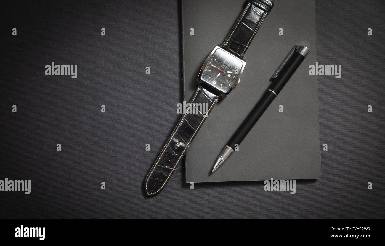 Black pen, wristwatch, notepad on the black background Stock Photo - Alamy