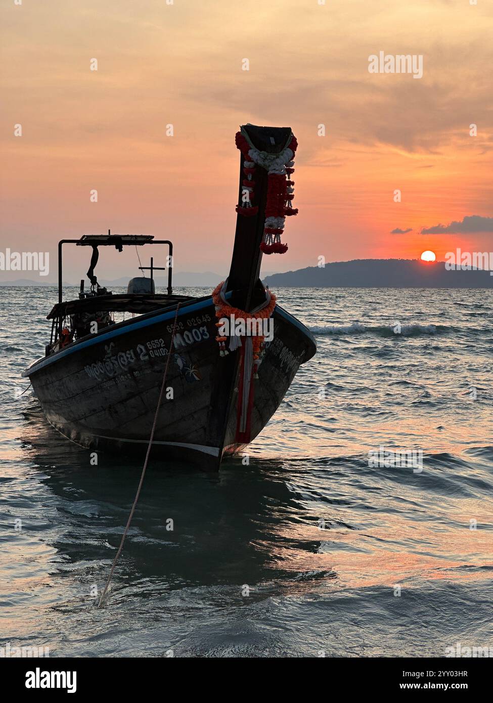 A boat floats in the ocean, with a sunset painting the sky Stock Photo ...