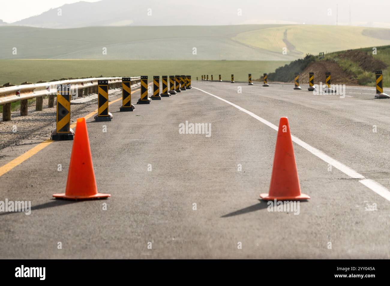 road closed showing orange cones and black and yellow chevron markings ...