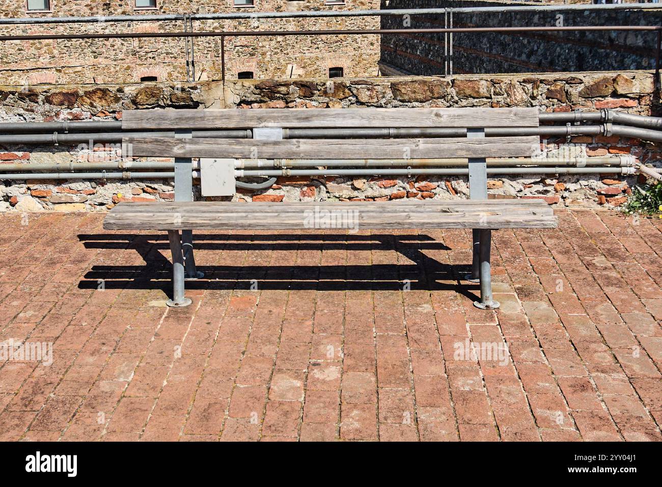 A rooftop bench on a brick terrace with industrial pipes and a scenic ...