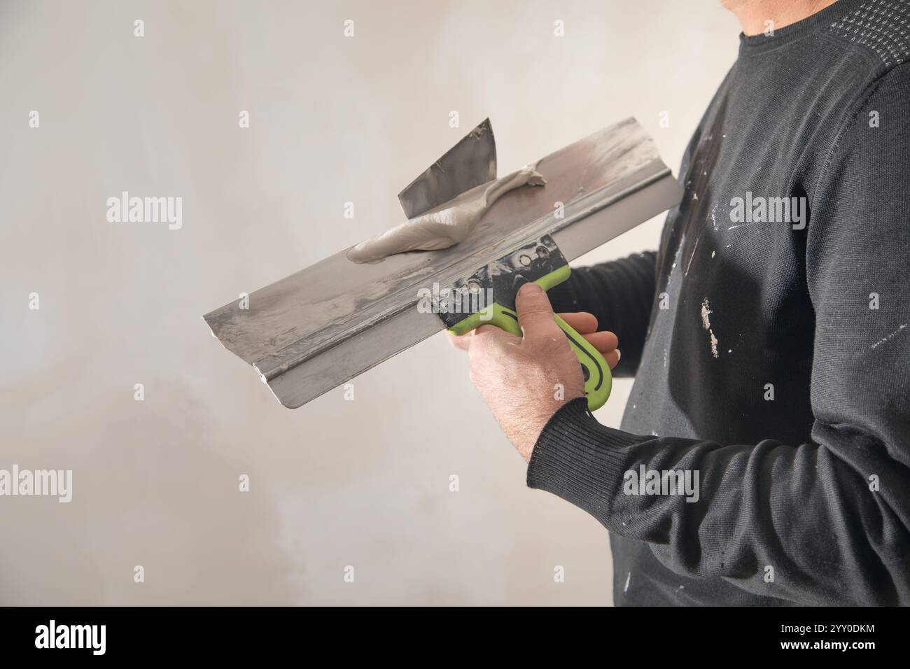Worker is applying putty on a wall. Renovating house Stock Photo - Alamy