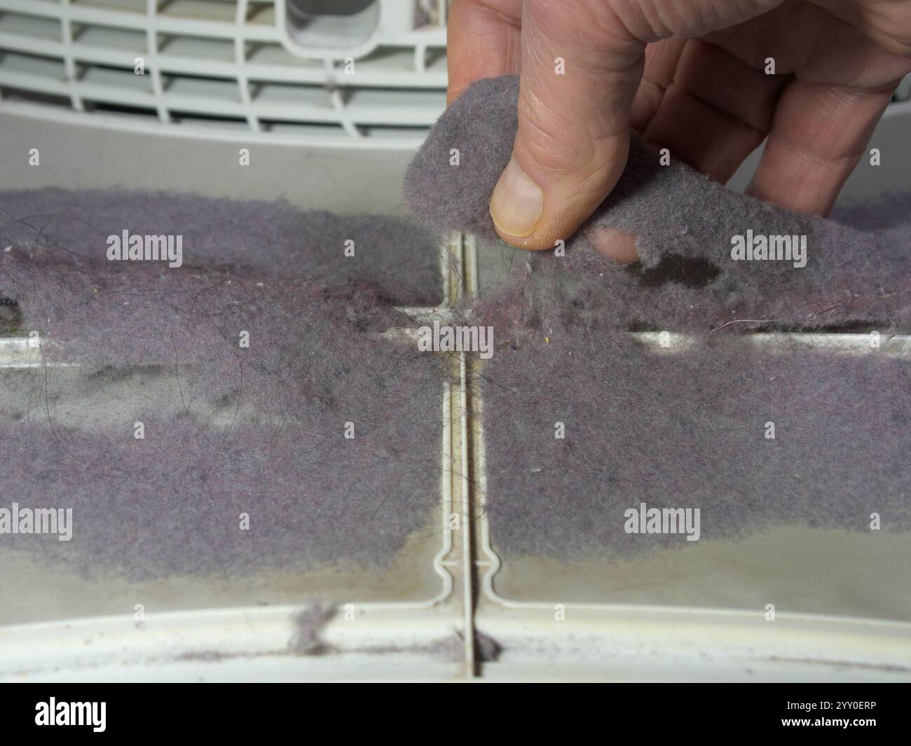 Closeup of a man’s hand removing the build-up of garment lint fluff ...