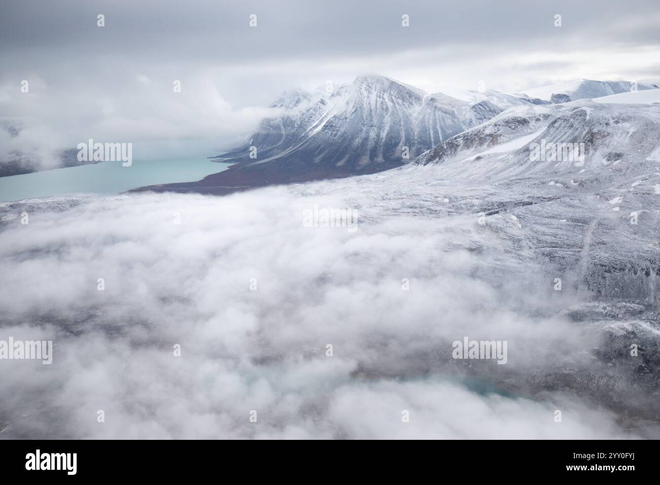 A helicopter view of the snowy mountains and fjords of Greenland in ...