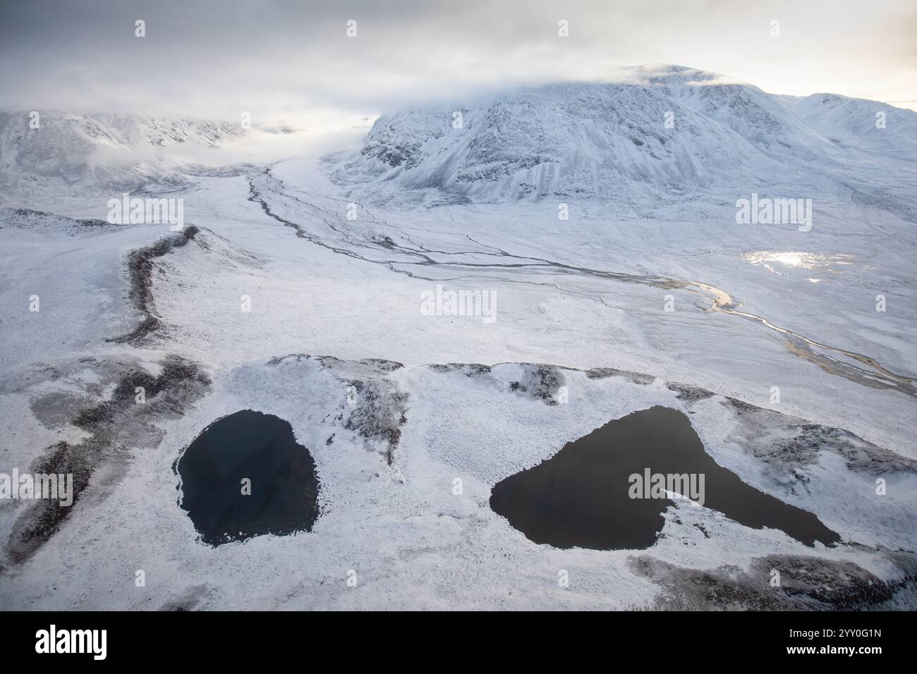 A helicopter view of the snowy mountains and fjords of Greenland in ...