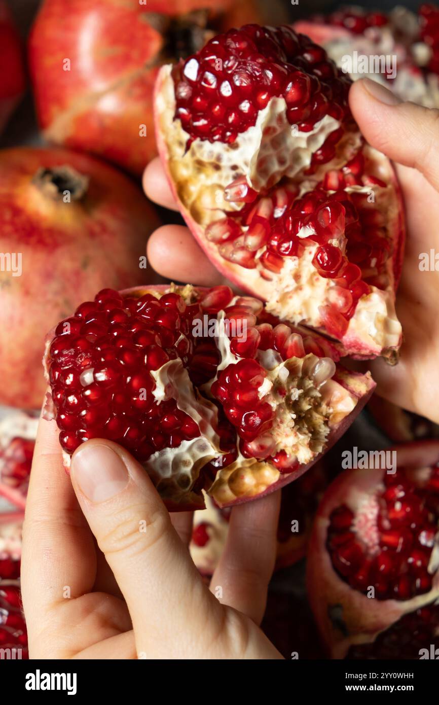 Hands open the pomegranate, separation into parts, pomegranates grains ...