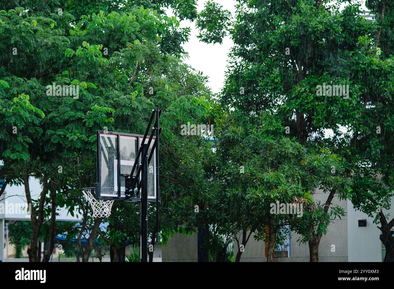 raining in the outdoor basketball field with a basketball hoop with ...