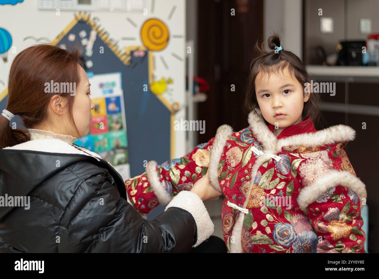 The young Chinese mother dresses her daughter for the celebration of ... The young Chinese mother dresses her daughter for the celebration of ...