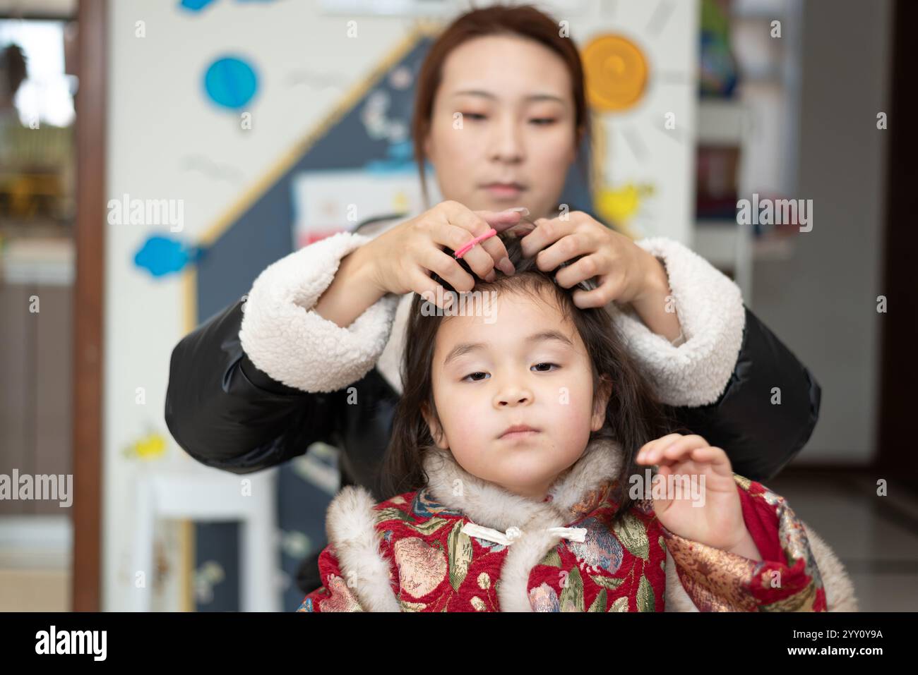The young Chinese mother is combing her daughter's hair. Her daughter ... The young Chinese mother is combing her daughter's hair. Her daughter ...