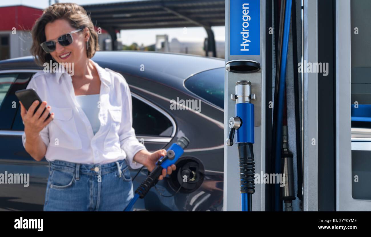 Woman holds a hydrogen fueling nozzle on a hydrogen filling station ...