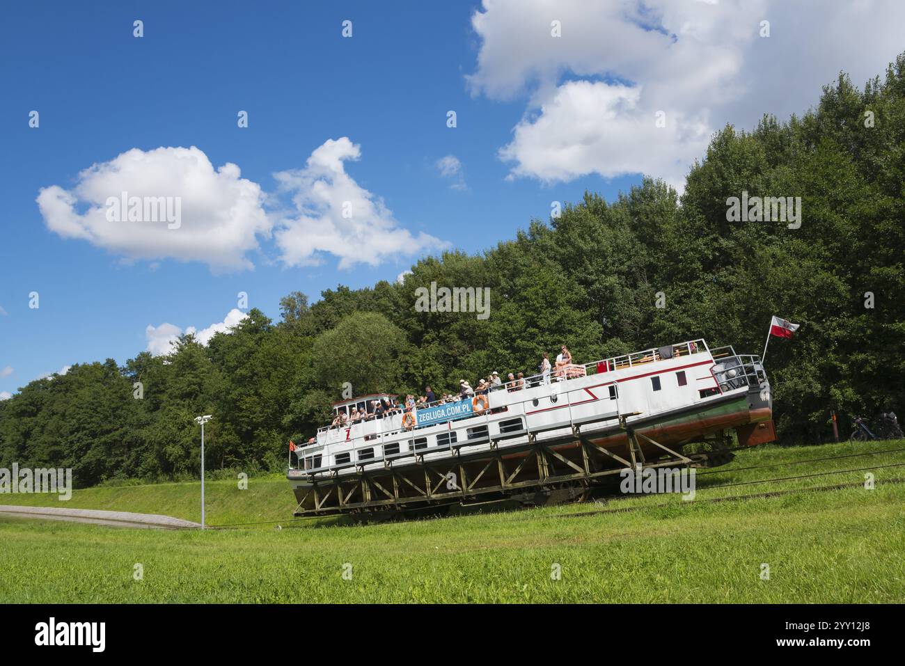 Boat with passengers on a railway carriage in front of a wooded ...