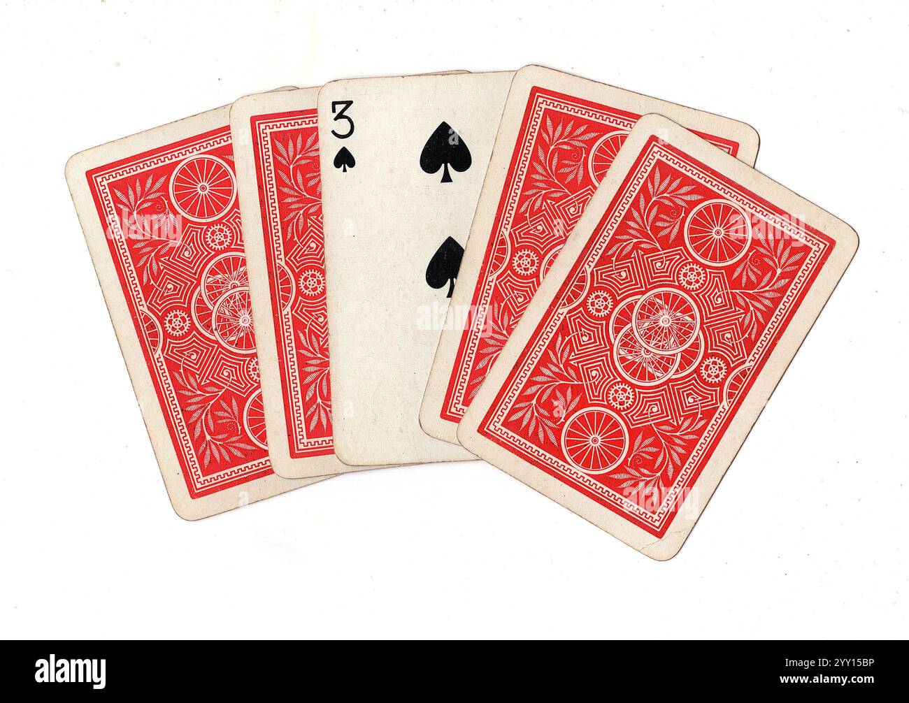 A hand of vintage playing card backs with the three of spades revealed ...